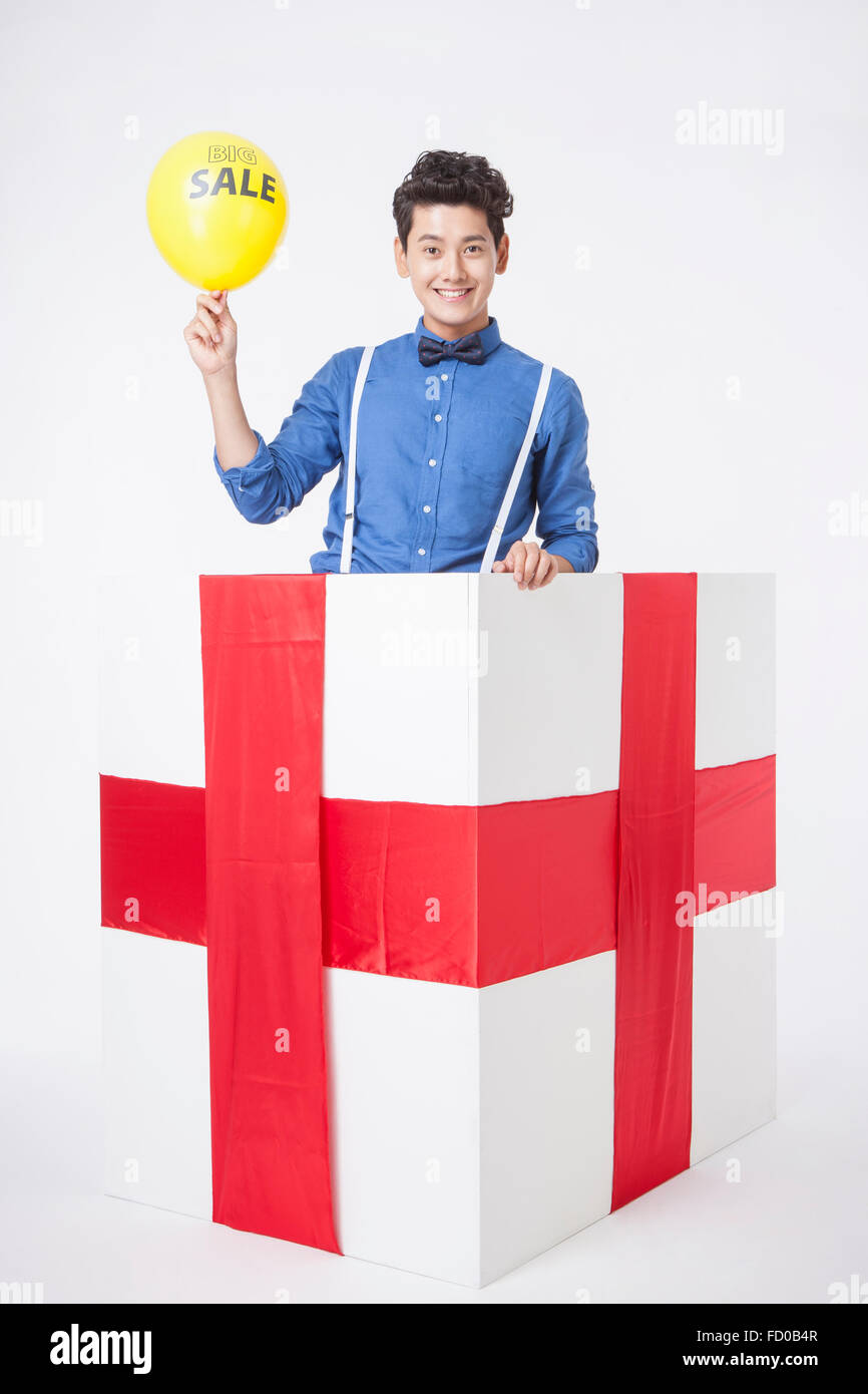 Man in blue shirt placed in a gift box staring forward and holding a ...