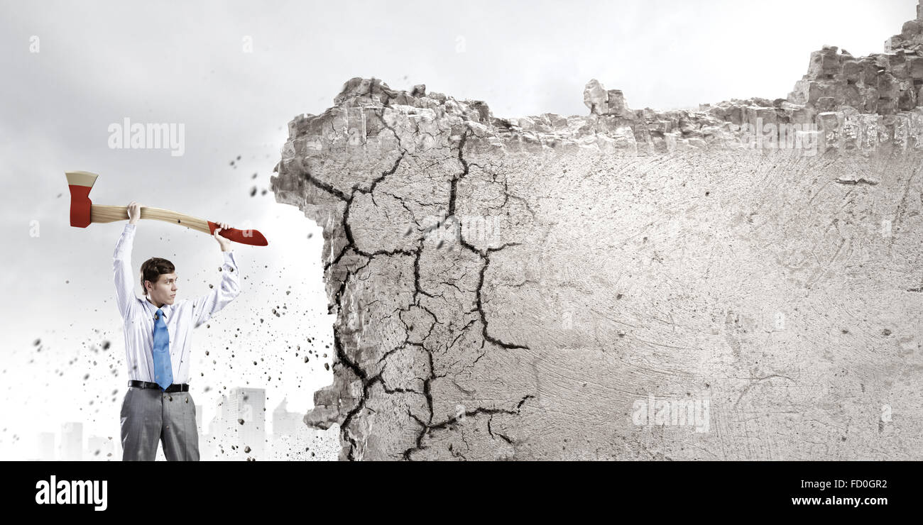 Young determined businessman crashing wall with axe Stock Photo - Alamy