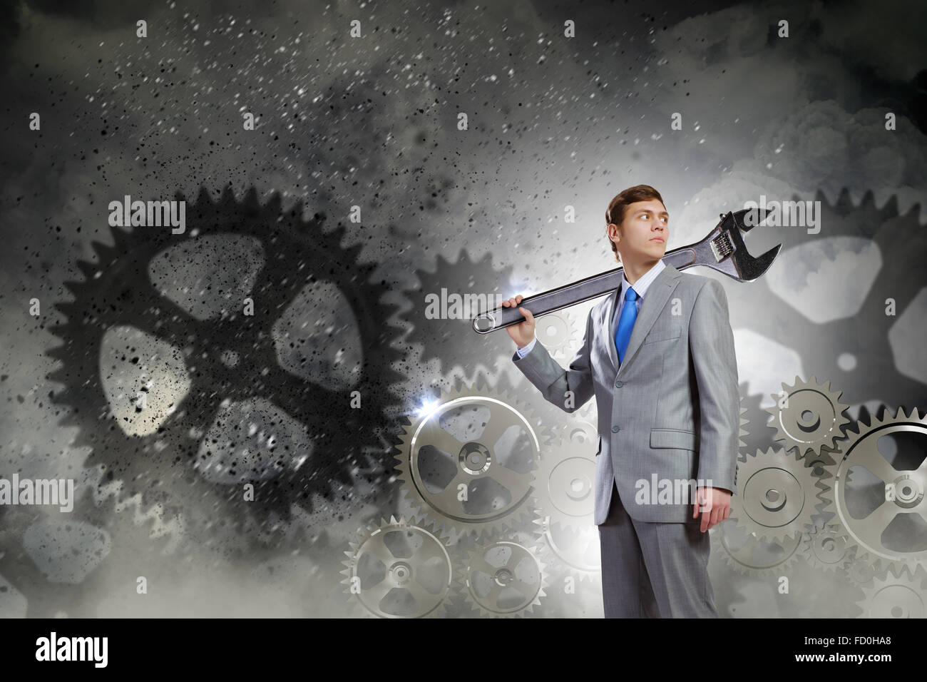 Young determined businessman with wrench on shoulder and cogwheels at ...