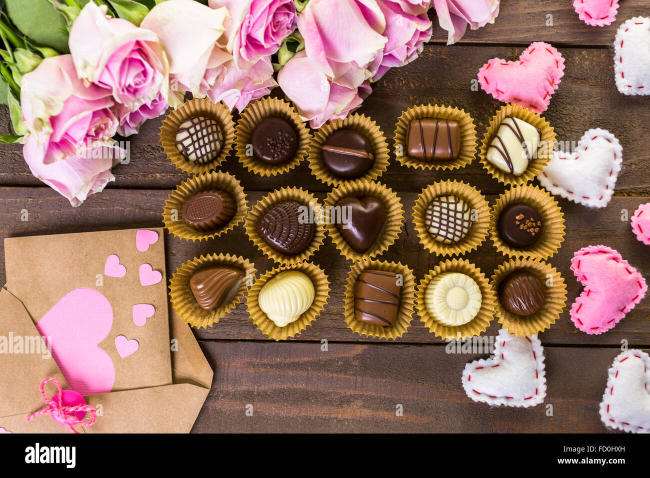 Assorted chocolated with pink roses on wood table Stock Photo - Alamy