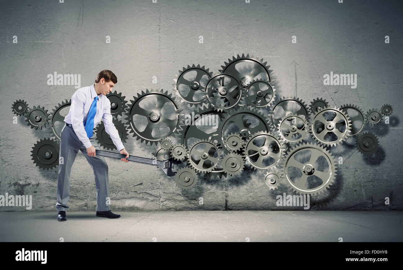 Young determined businessman with wrench fixing mechanism Stock Photo ...