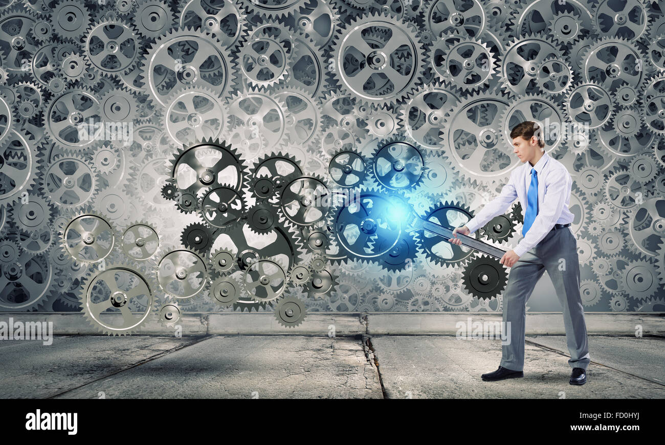 Young determined businessman with wrench fixing mechanism Stock Photo ...