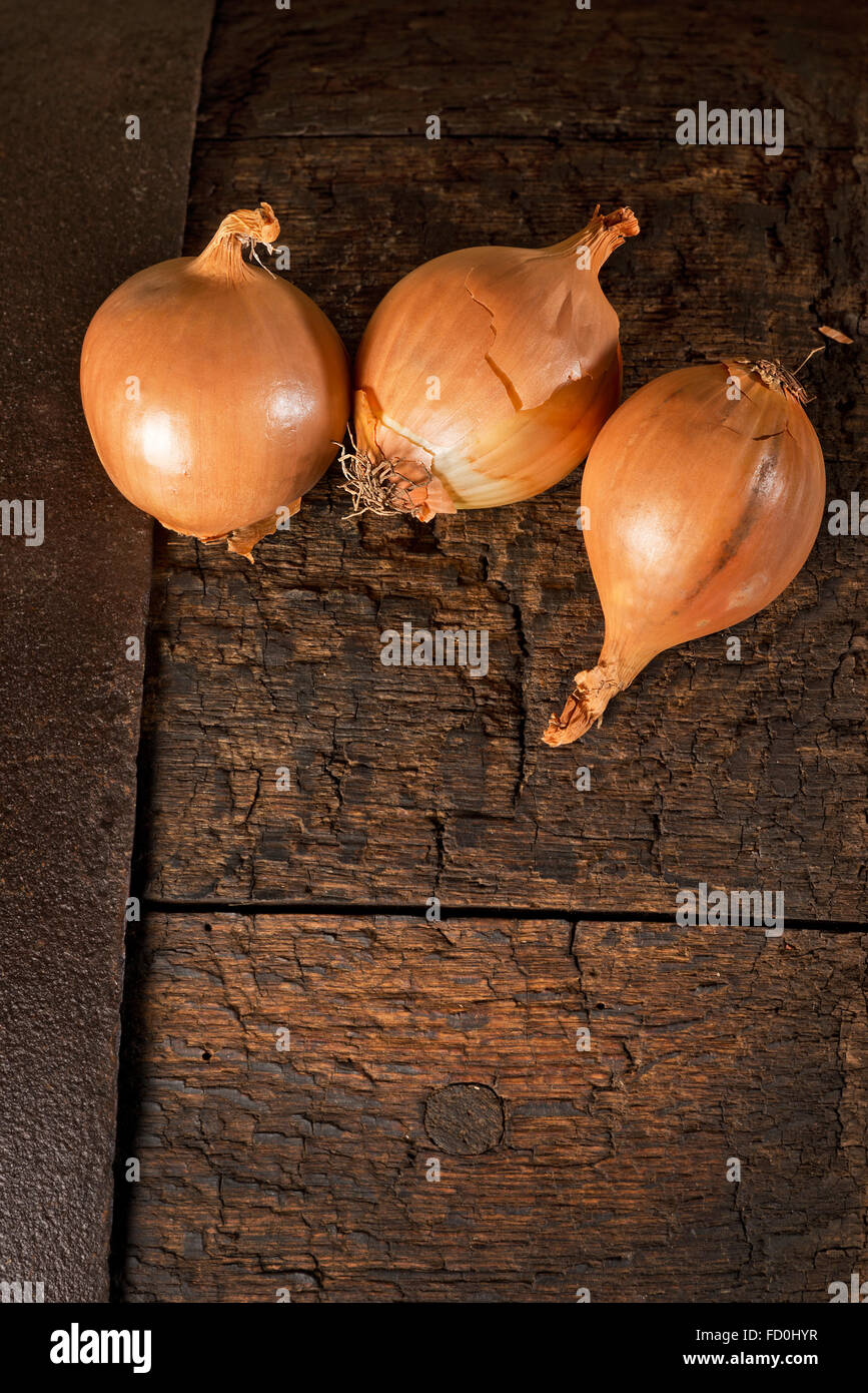 three onions on the old dark table Stock Photo - Alamy
