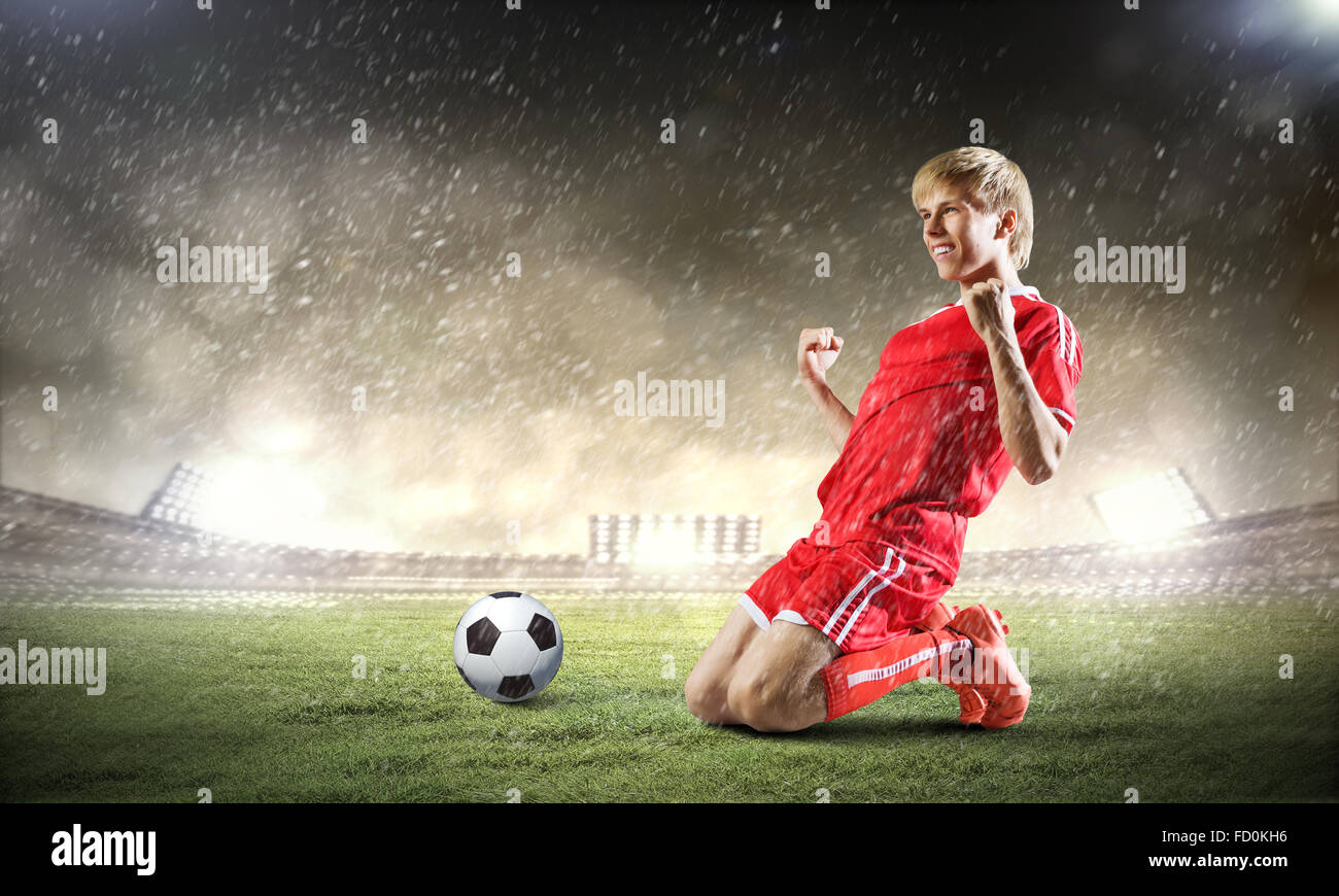 Football player standing on knees and screaming with joy Stock Photo ...