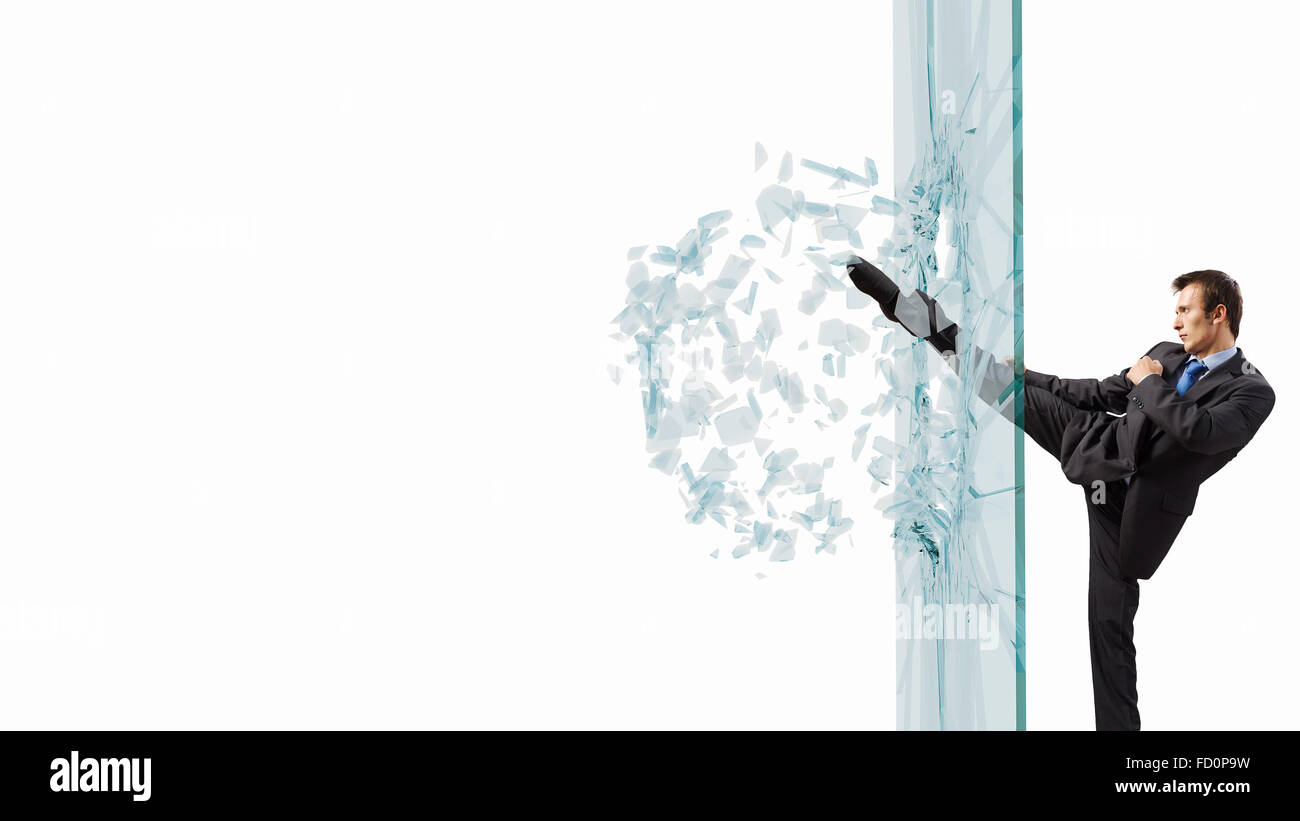 Young determined businessman breaking glass with karate kick Stock ...