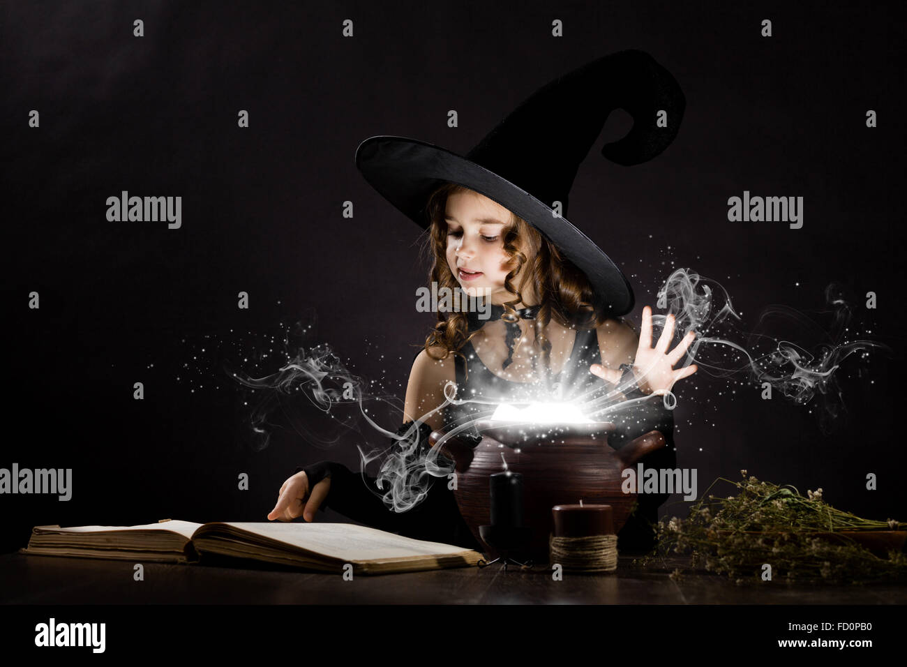 Little Halloween witch reading conjure above pot Stock Photo - Alamy