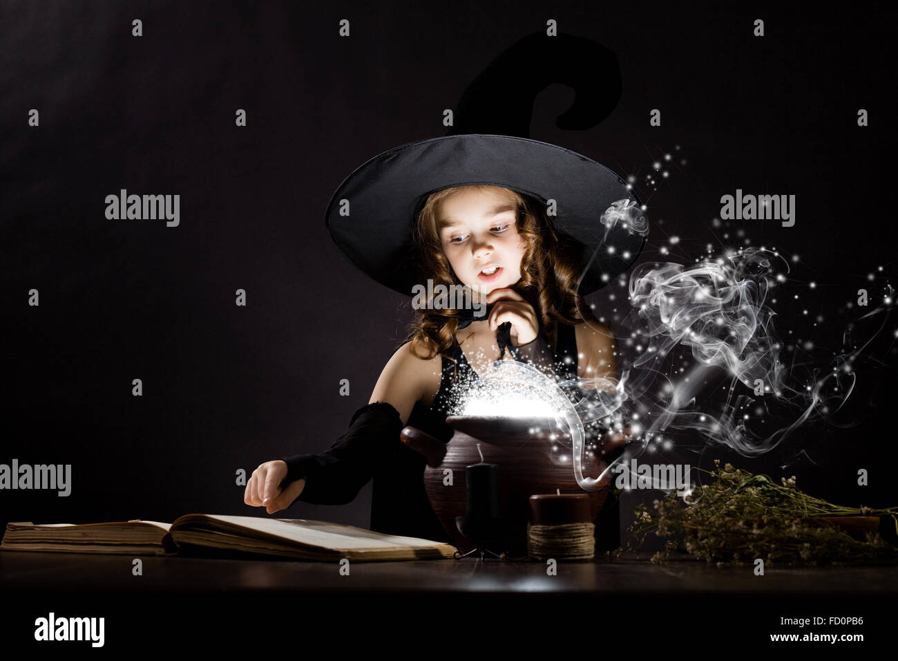 Little Halloween witch reading conjure above pot Stock Photo - Alamy