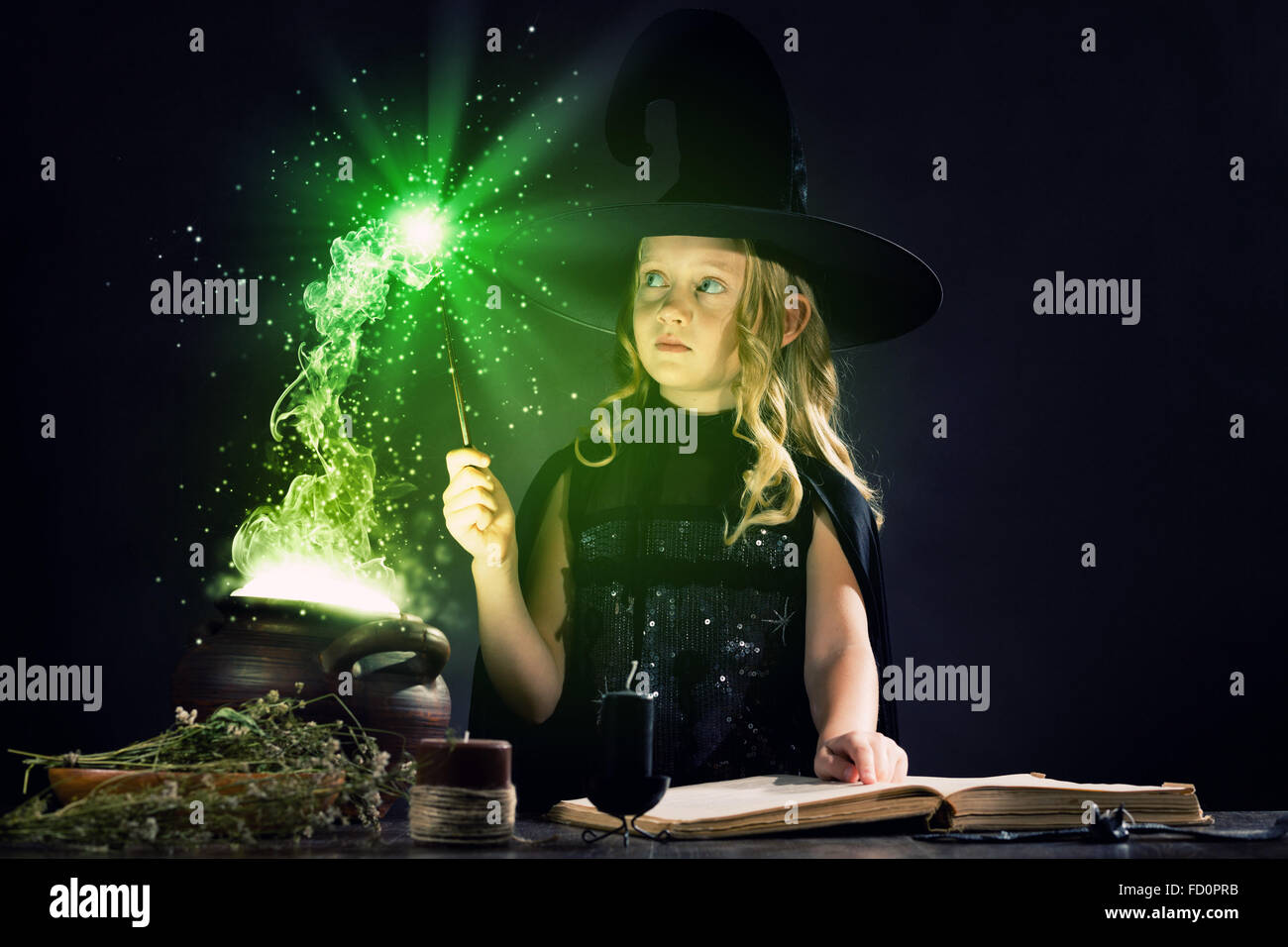 Little Halloween witch reading conjure above pot Stock Photo - Alamy