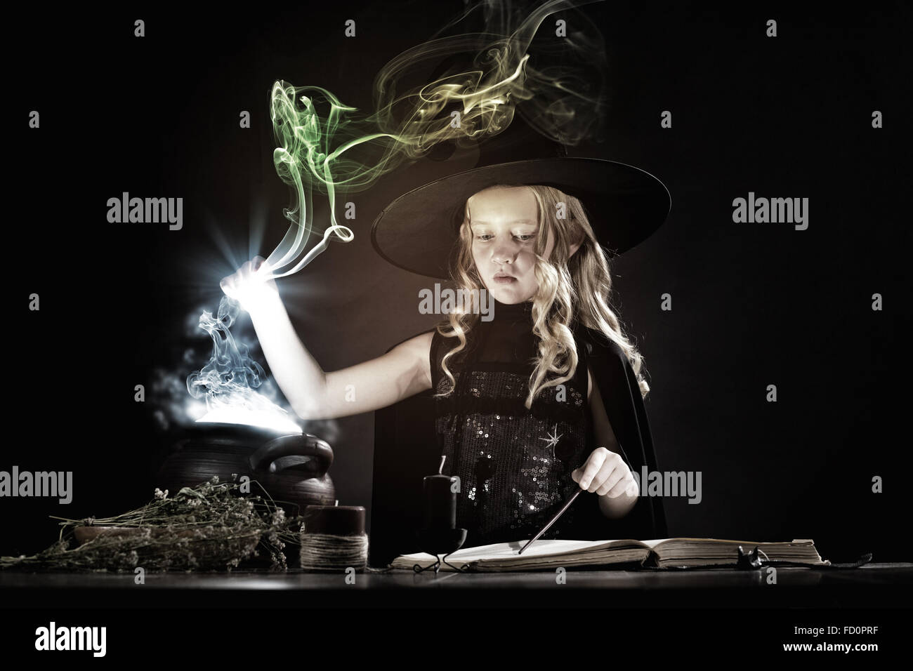Little Halloween witch reading conjure above pot Stock Photo - Alamy