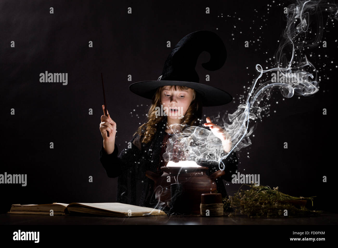 Little Halloween witch reading conjure above pot Stock Photo - Alamy
