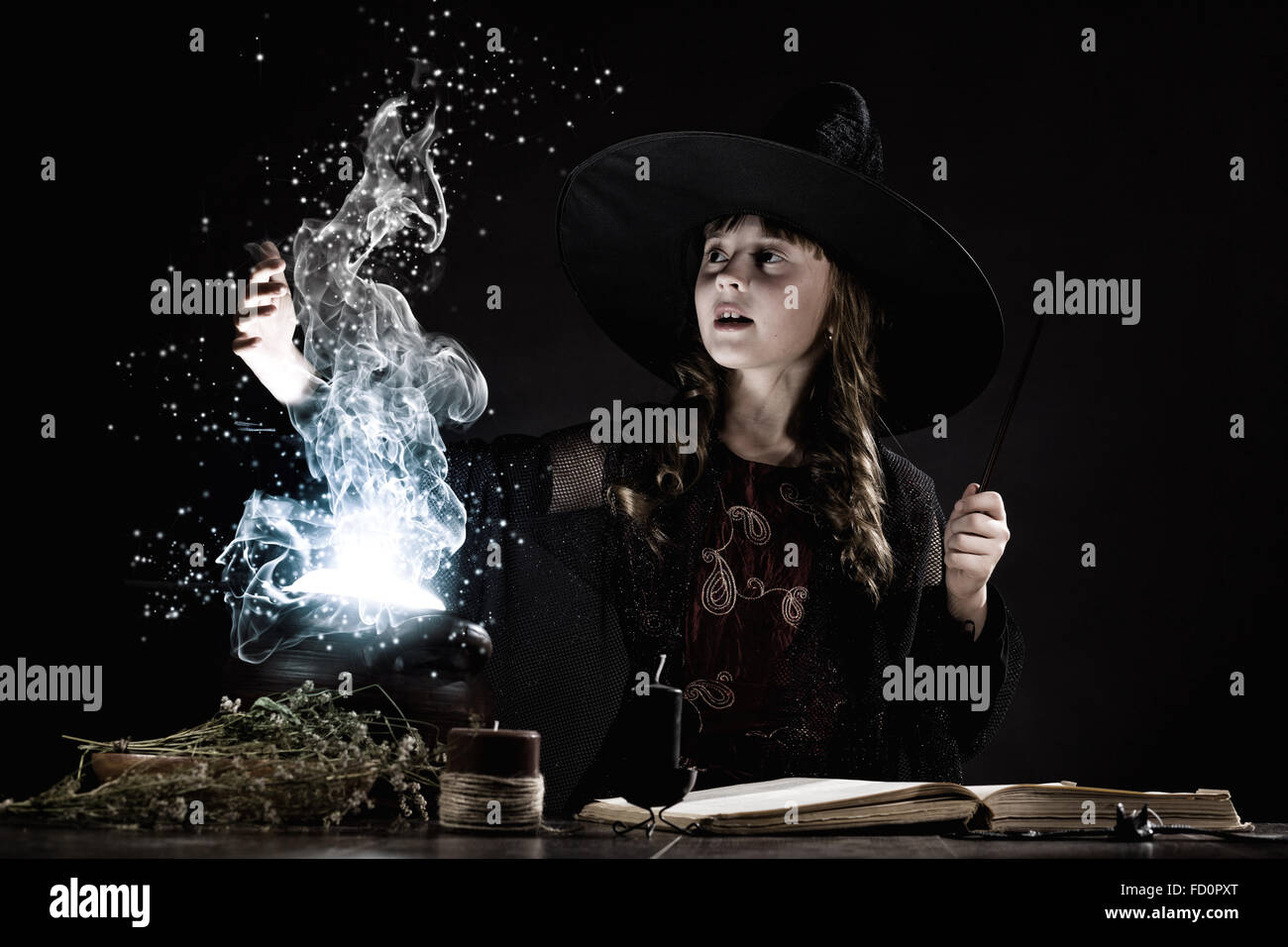 Little Halloween witch making magic with stick Stock Photo - Alamy