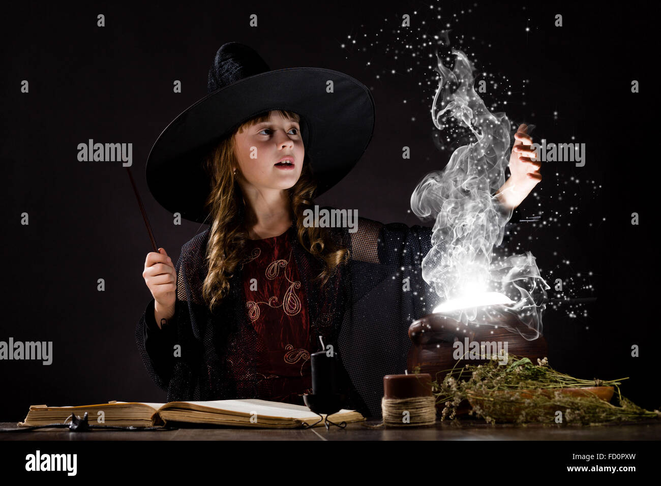 Little Halloween witch reading conjure above pot Stock Photo - Alamy