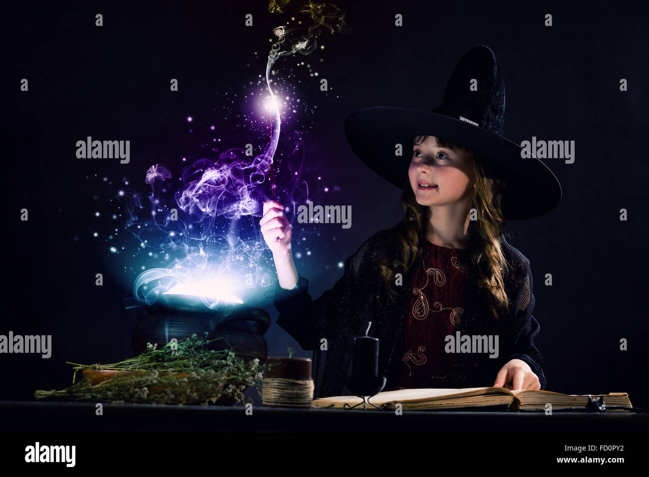 Little Halloween witch making magic with stick Stock Photo - Alamy