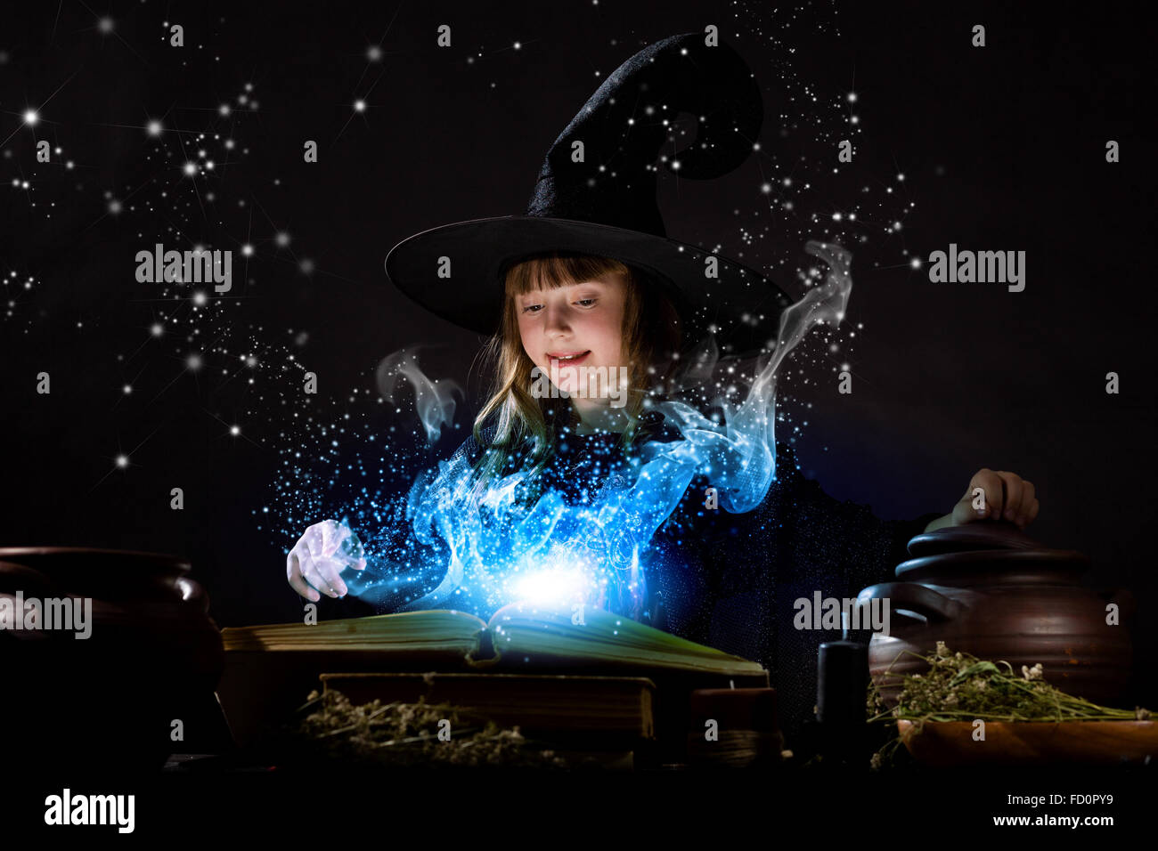 Little Halloween witch making magic with stick Stock Photo - Alamy