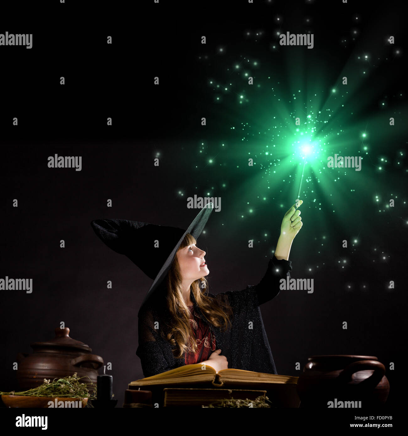 Little Halloween witch making magic with stick Stock Photo - Alamy