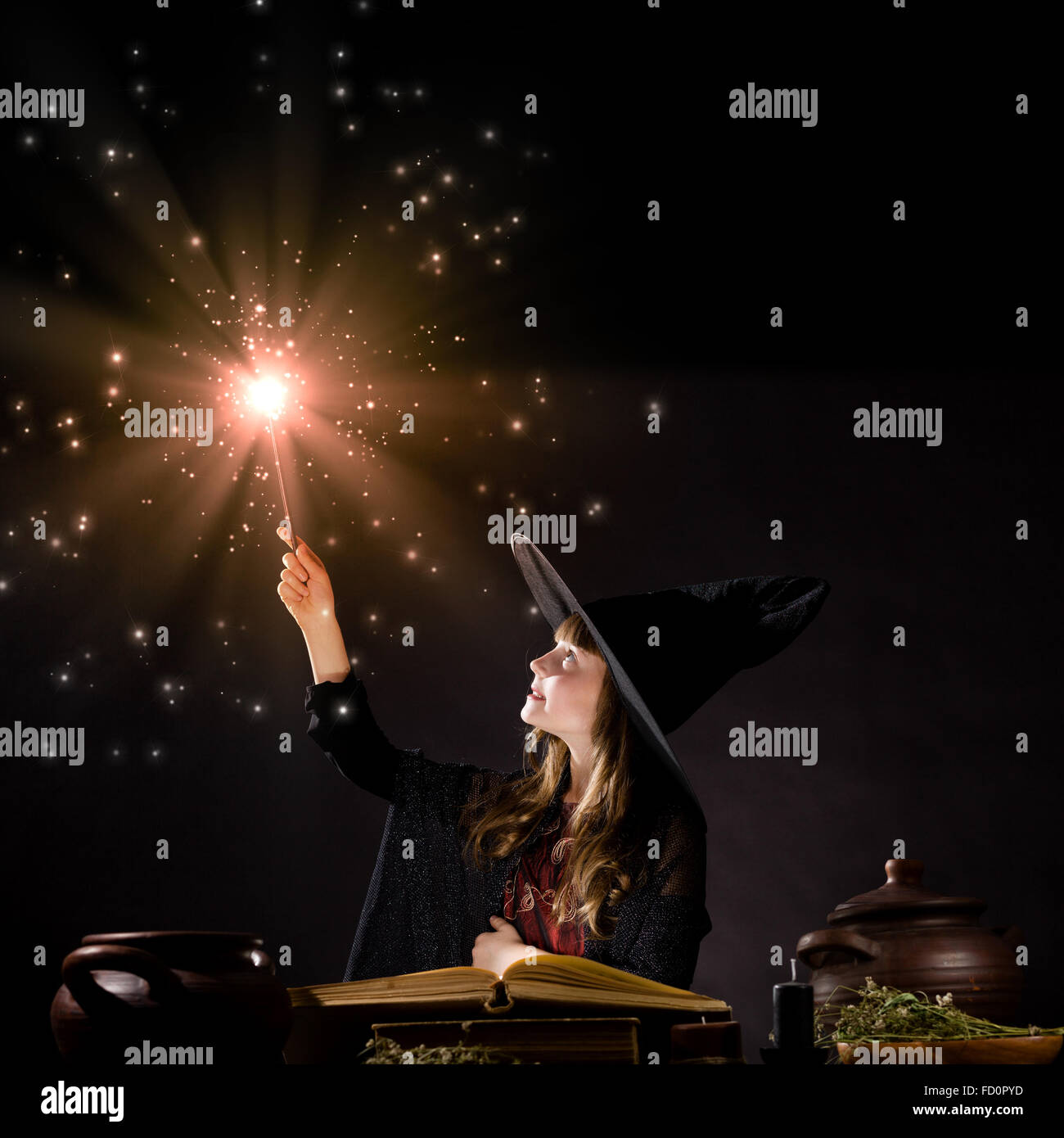 Little Halloween witch making magic with stick Stock Photo - Alamy