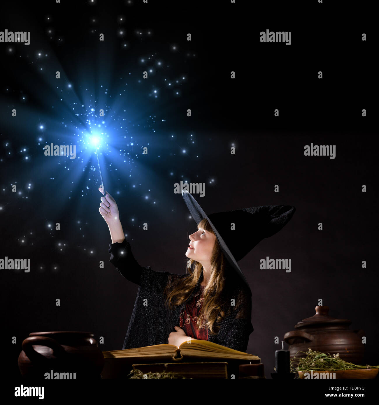 Little Halloween witch making magic with stick Stock Photo - Alamy