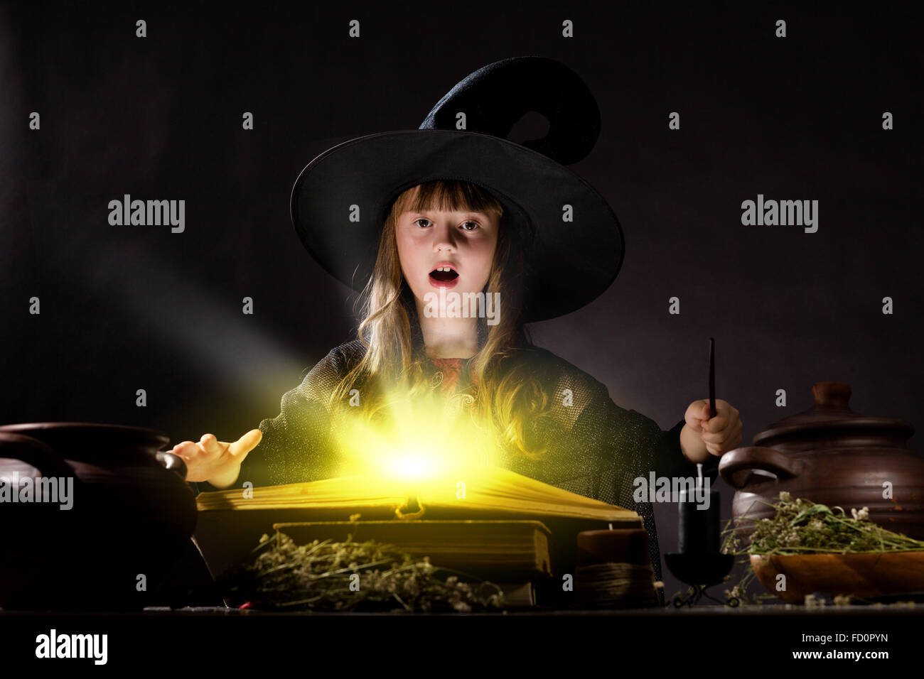 Little Halloween witch making magic with stick Stock Photo - Alamy