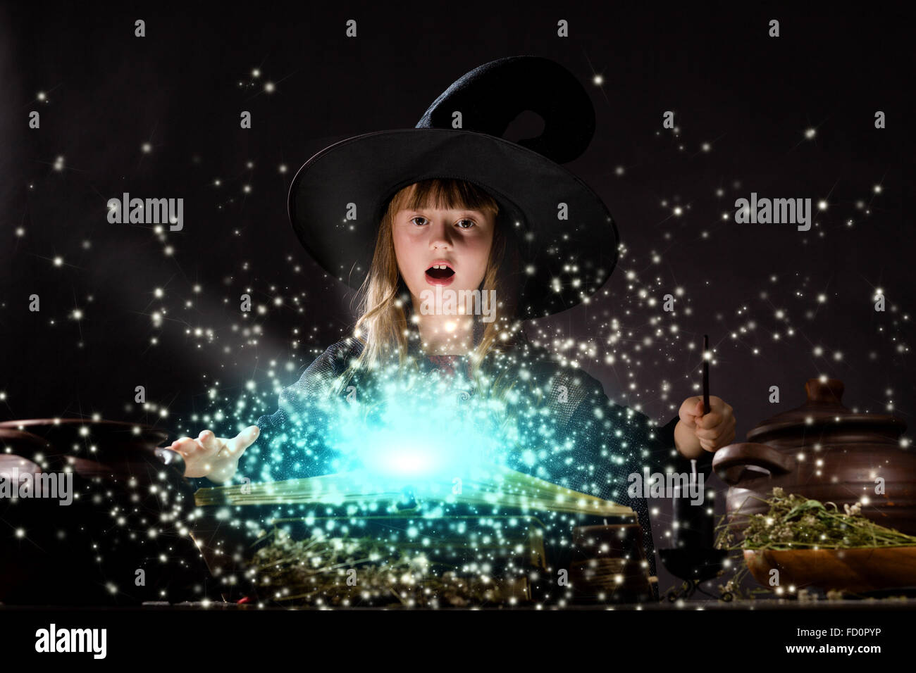 Little Halloween witch making magic with stick Stock Photo - Alamy