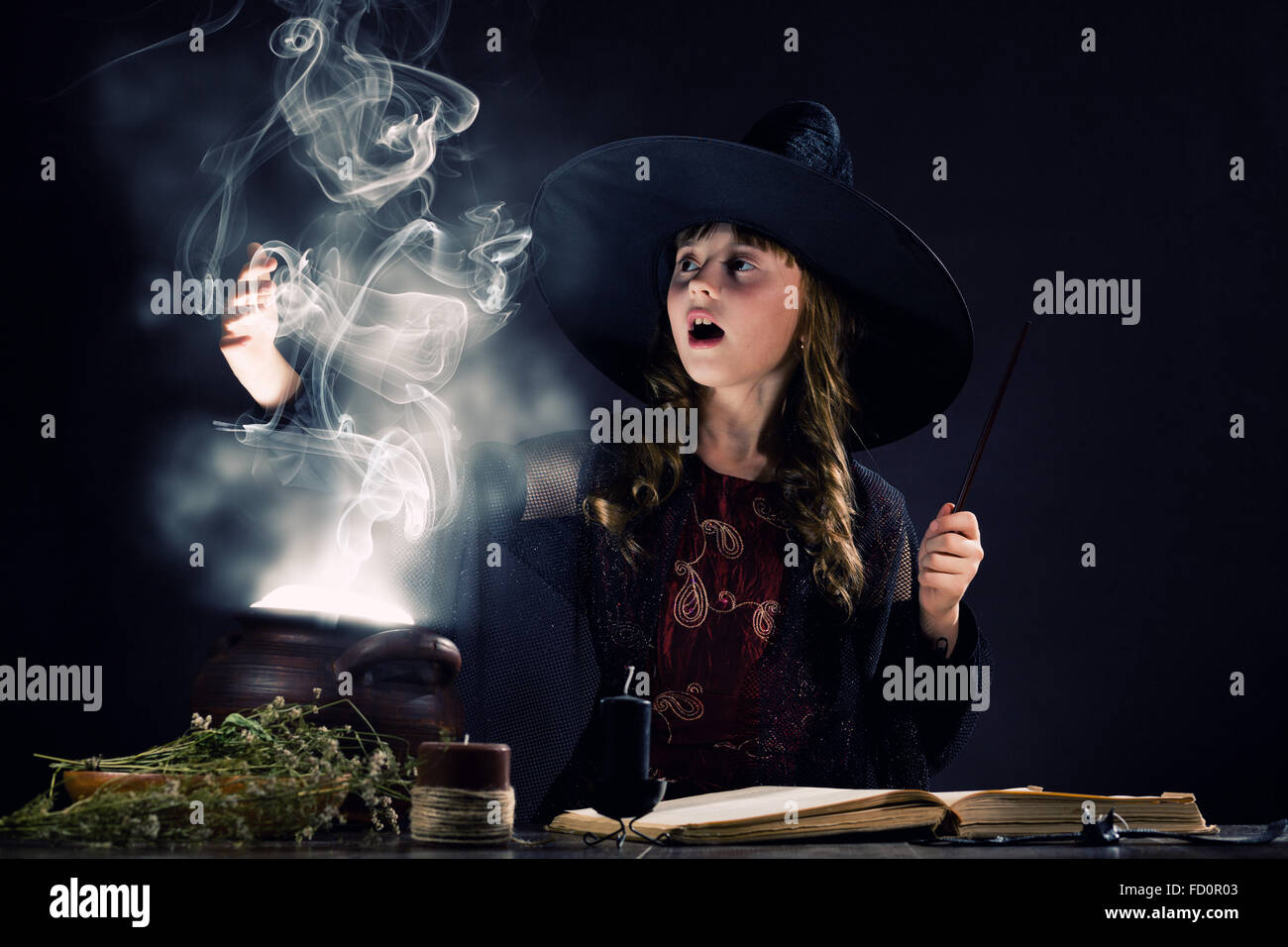 Little Halloween witch reading conjure above pot Stock Photo - Alamy