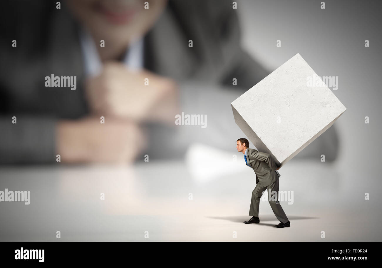 Businesswoman looking at miniature of man carrying white cube on back ...