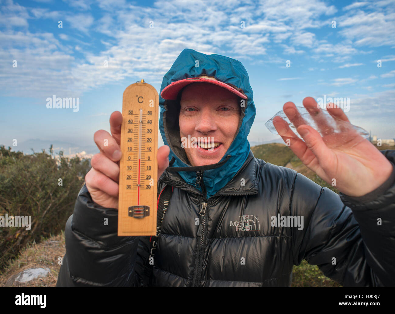 A man holds ice and a thermometer, on Kowloon peak, as temperatures ...
