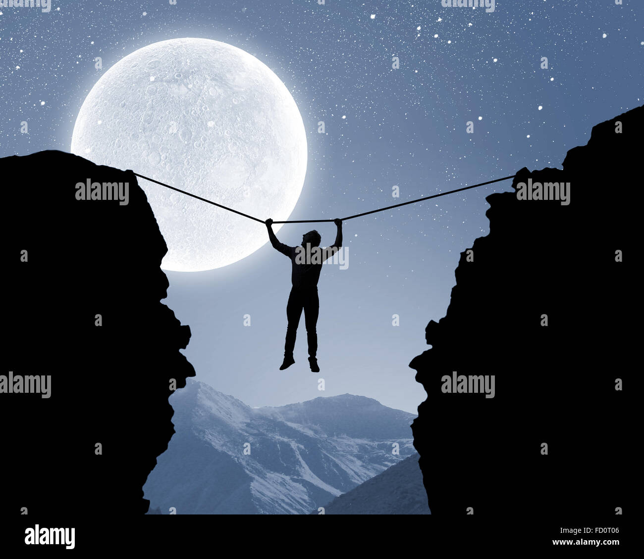 Silhouette of man hanging on rope above mountain gap Stock Photo - Alamy