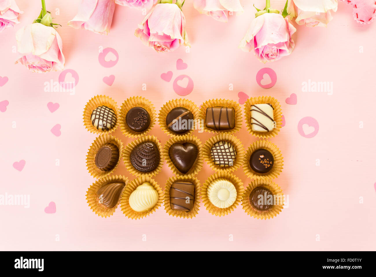 Assorted chocolates with pink roses on pink background Stock Photo - Alamy