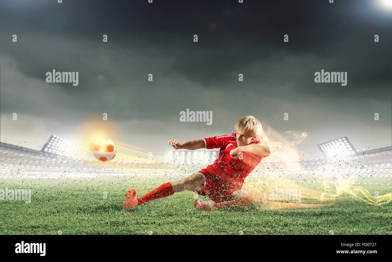 Young football player on stadium doing slide tackle Stock Photo - Alamy