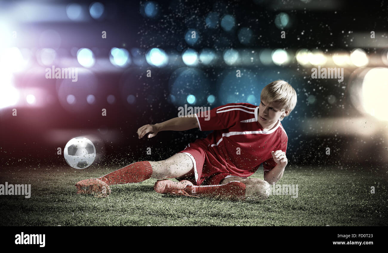 Young football player on stadium doing slide tackle Stock Photo - Alamy