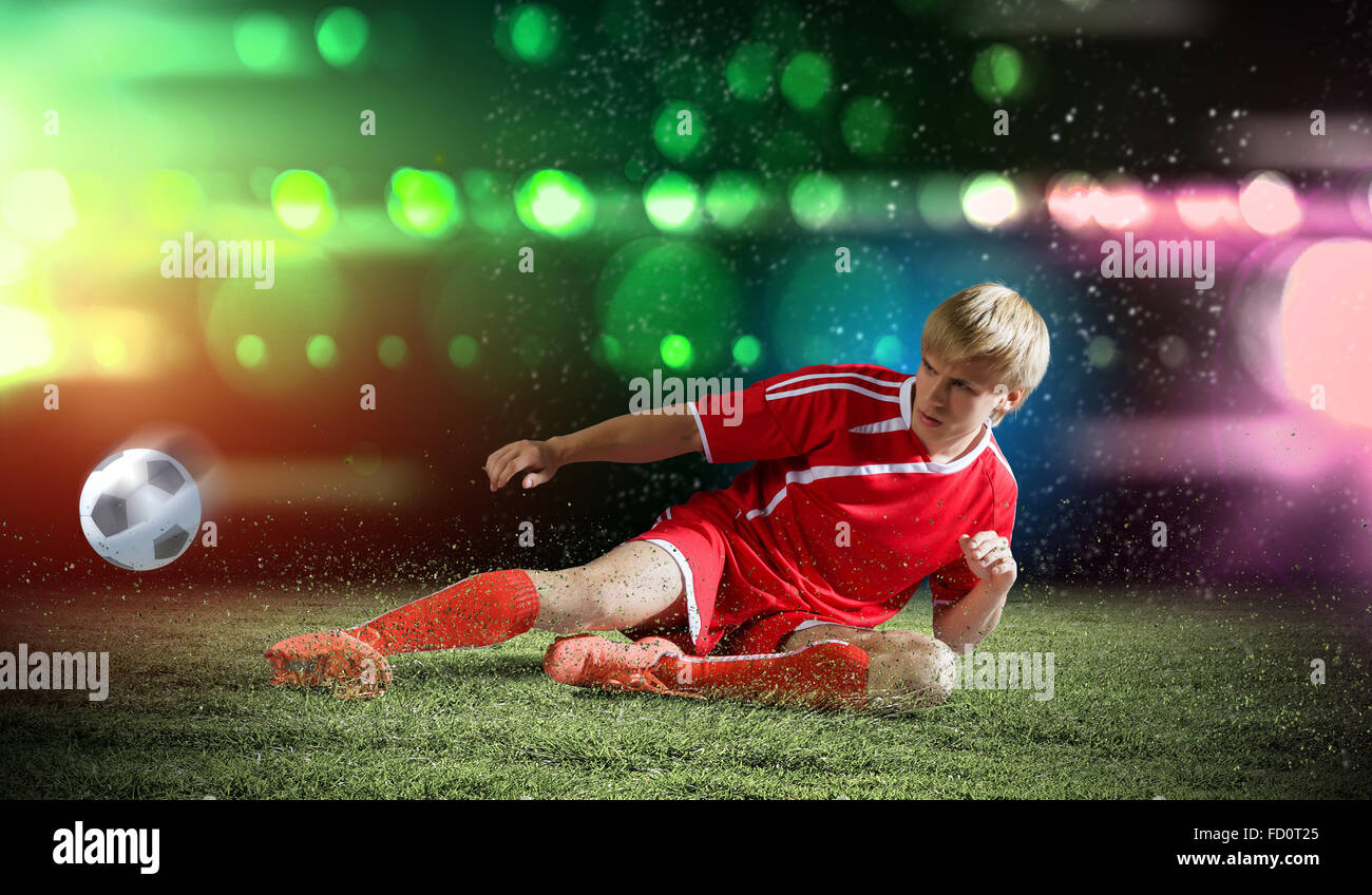 Young football player on stadium doing slide tackle Stock Photo - Alamy