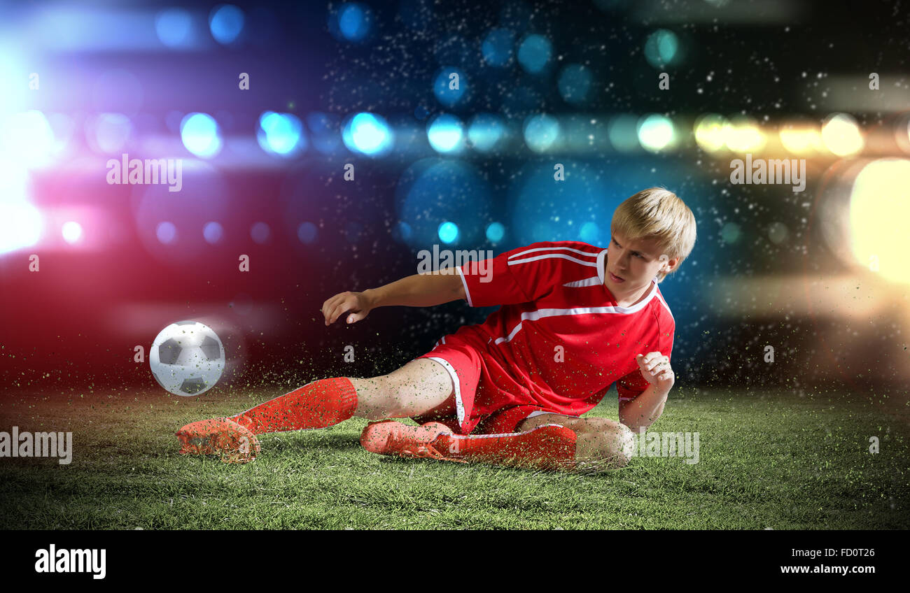 Young football player on stadium doing slide tackle Stock Photo - Alamy