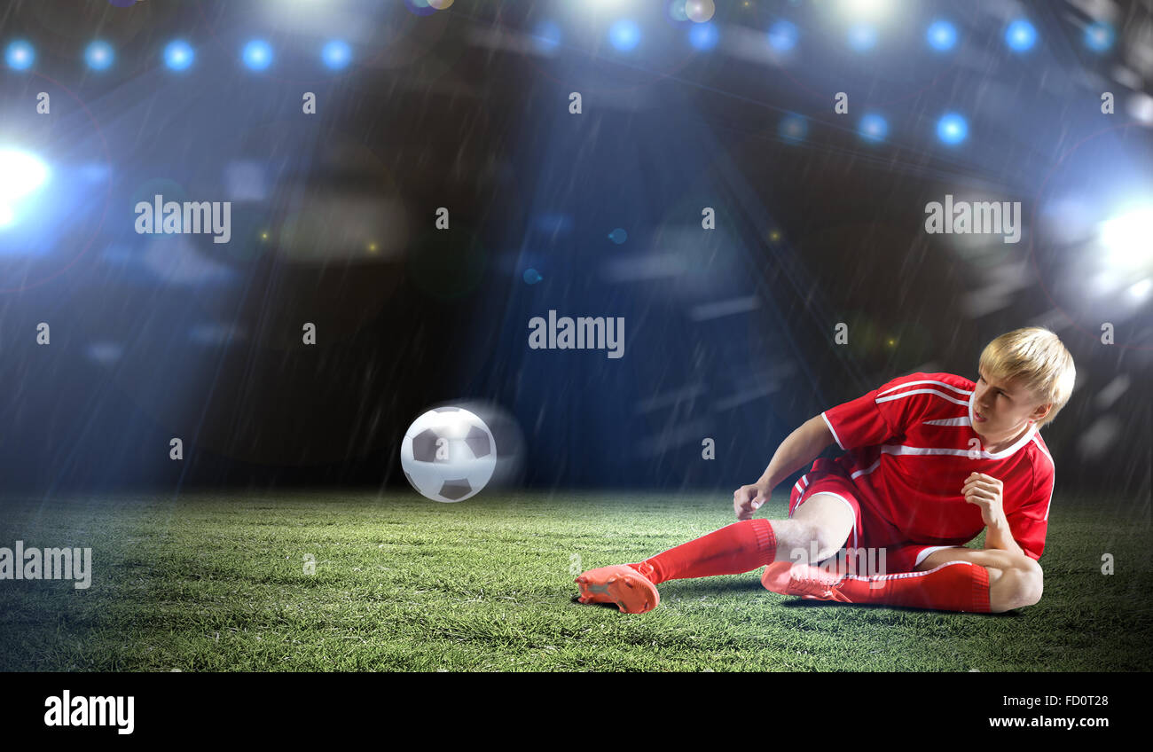 Young football player on stadium doing slide tackle Stock Photo - Alamy