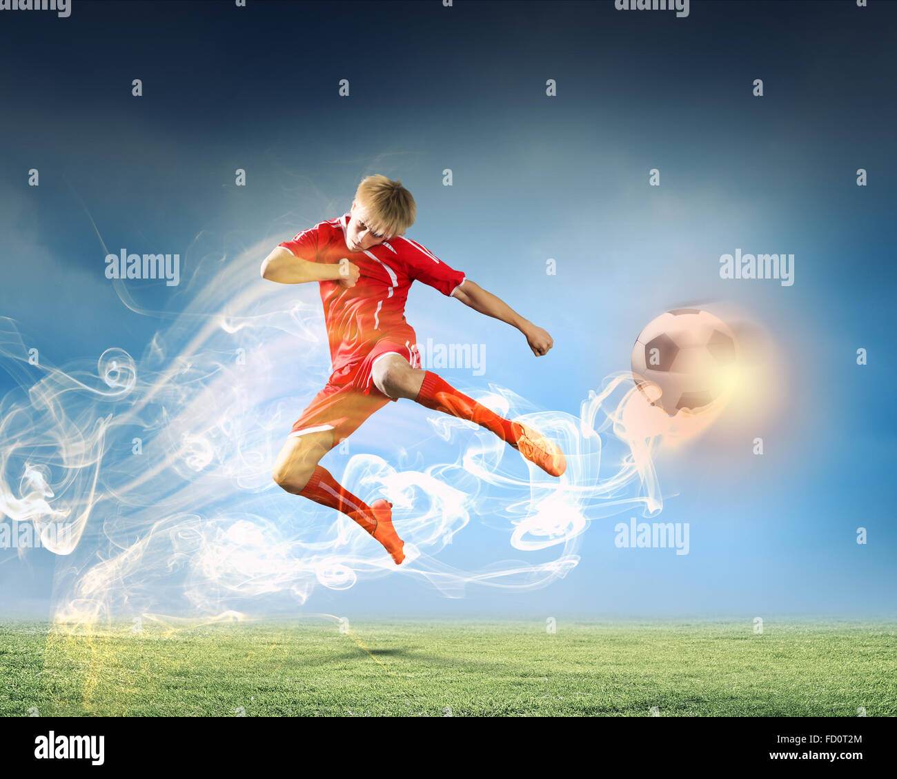 Young football player on stadium kicking ball in jump Stock Photo - Alamy