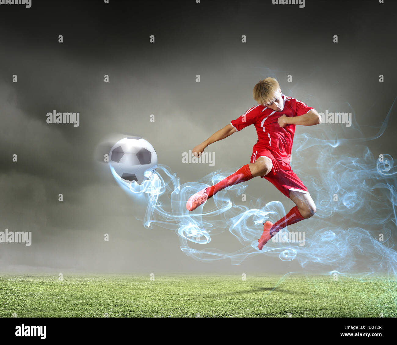 Young football player on stadium kicking ball in jump Stock Photo - Alamy