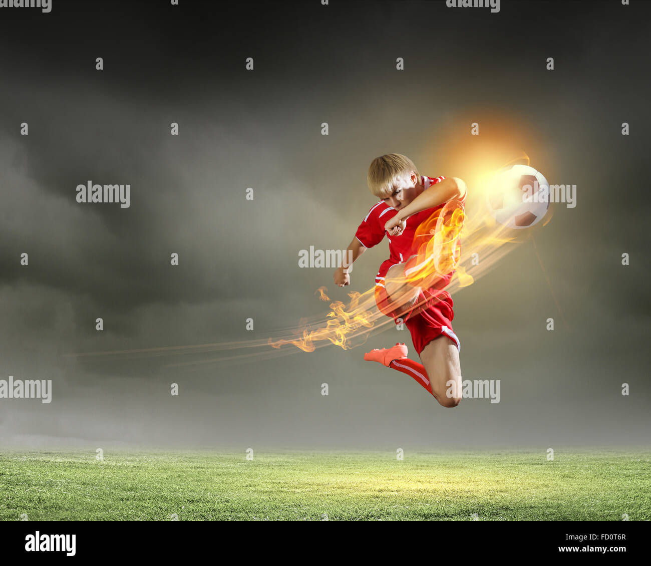 Young football player on stadium kicking ball in jump hi-res stock ...