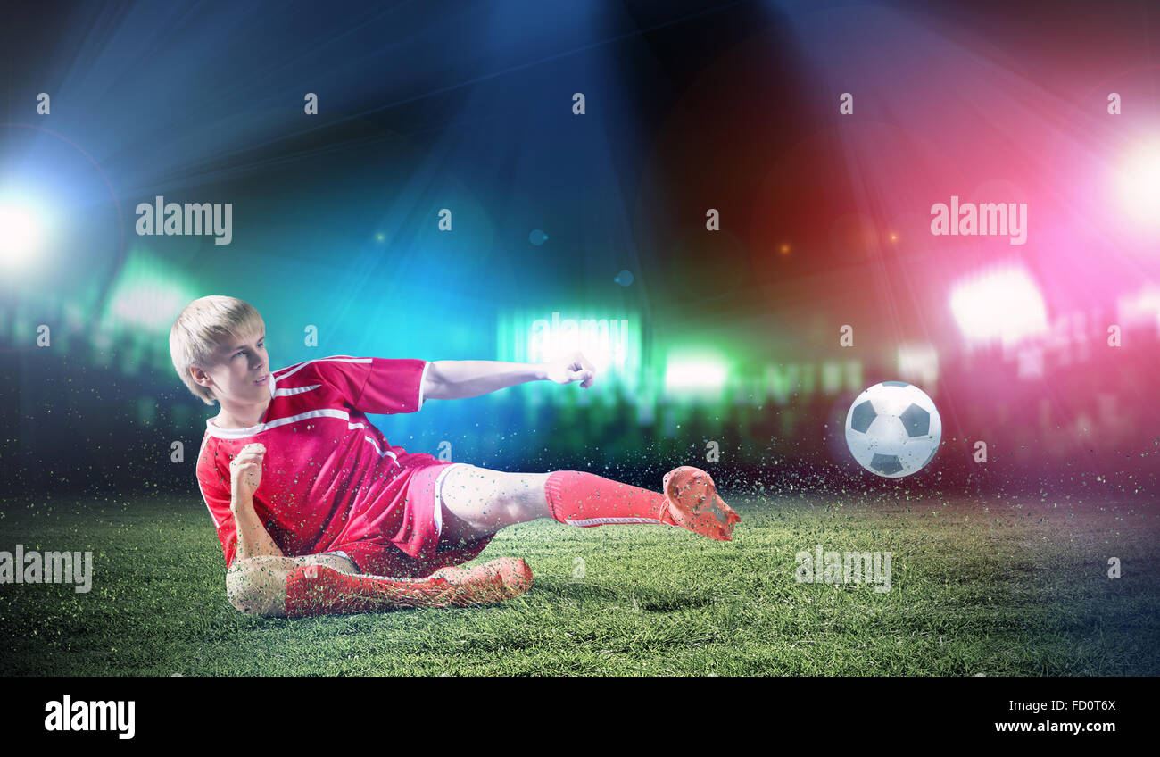 Young football player on stadium doing slide tackle Stock Photo - Alamy