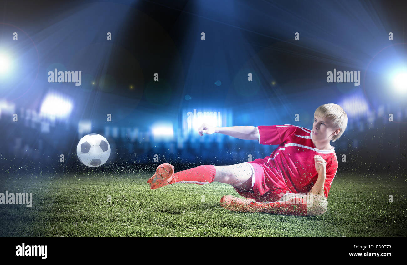 Young football player on stadium doing slide tackle Stock Photo - Alamy