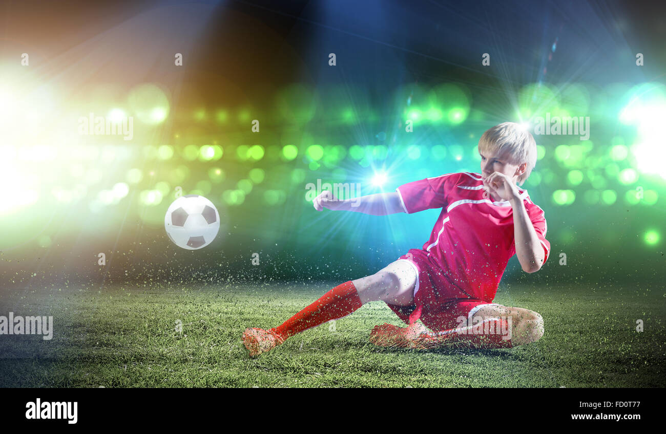 Young football player on stadium doing slide tackle Stock Photo - Alamy
