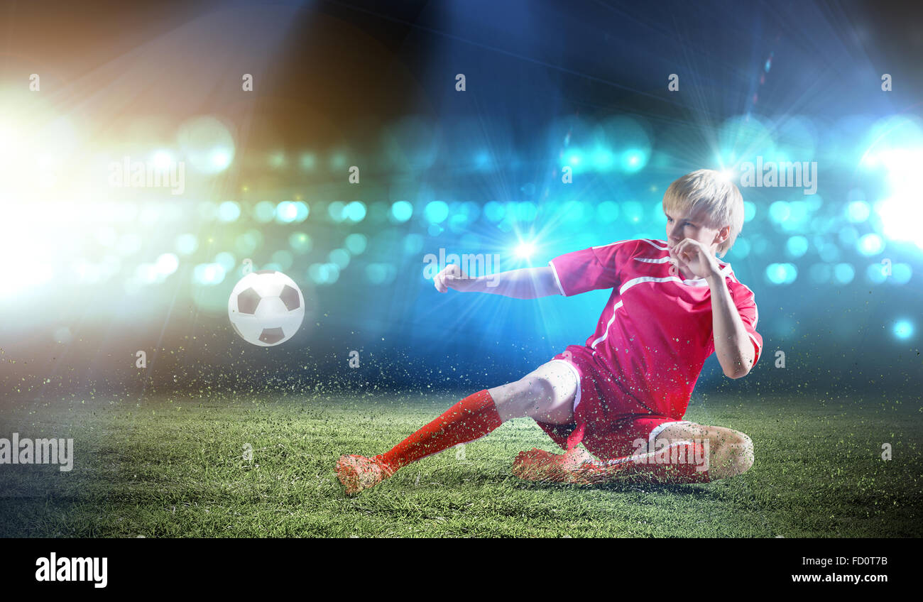 Young football player on stadium doing slide tackle Stock Photo - Alamy