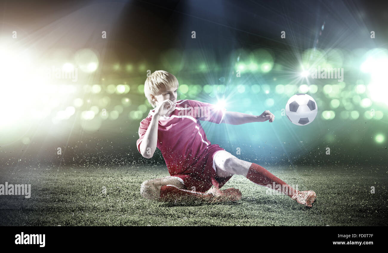 Young football player on stadium doing slide tackle Stock Photo - Alamy