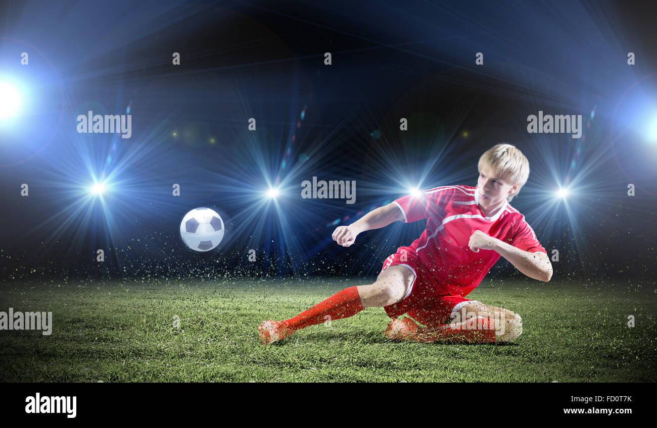 Young football player on stadium doing slide tackle Stock Photo - Alamy
