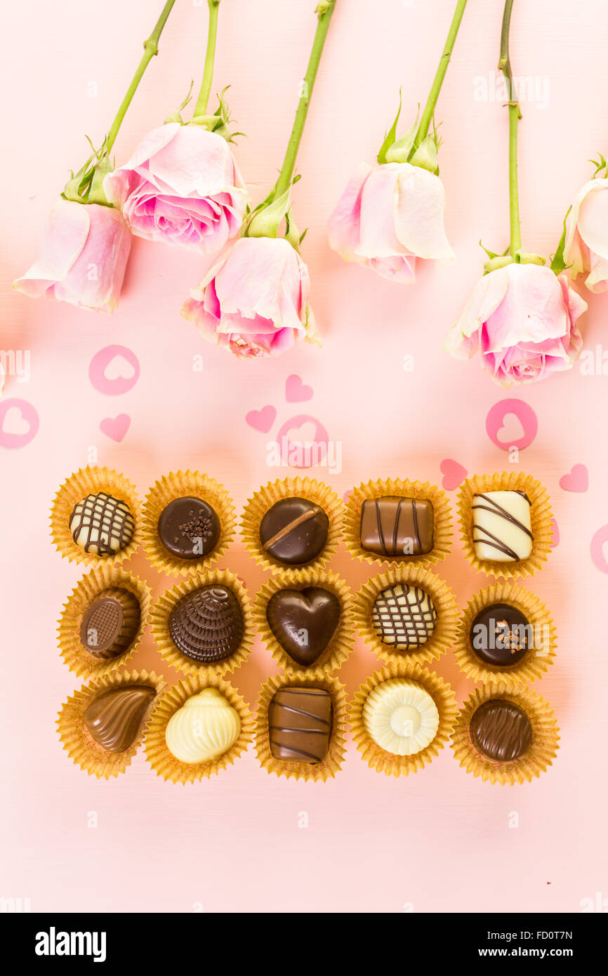 Assorted chocolates with pink roses on pink background Stock Photo - Alamy