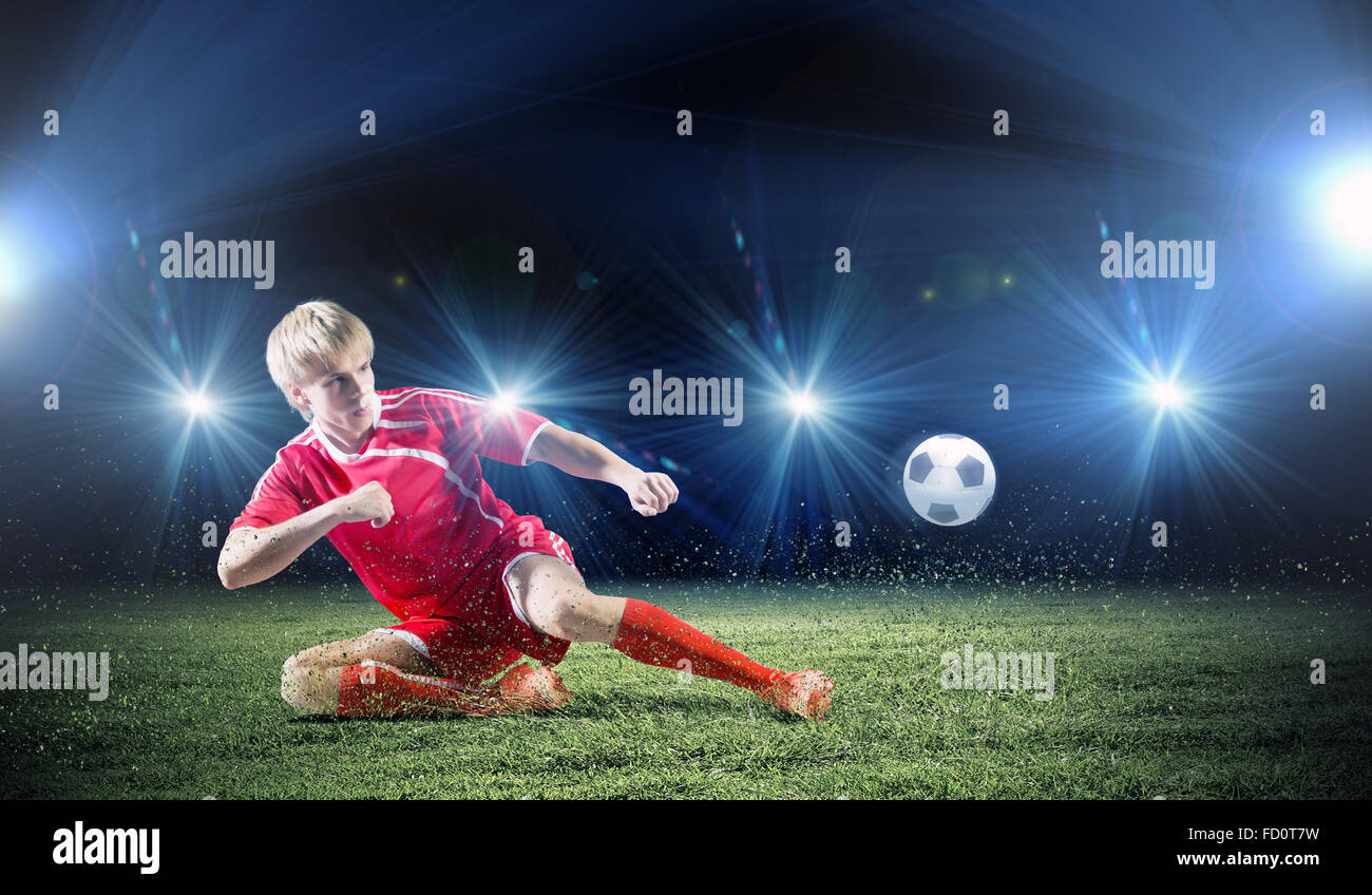 Young football player on stadium doing slide tackle Stock Photo - Alamy