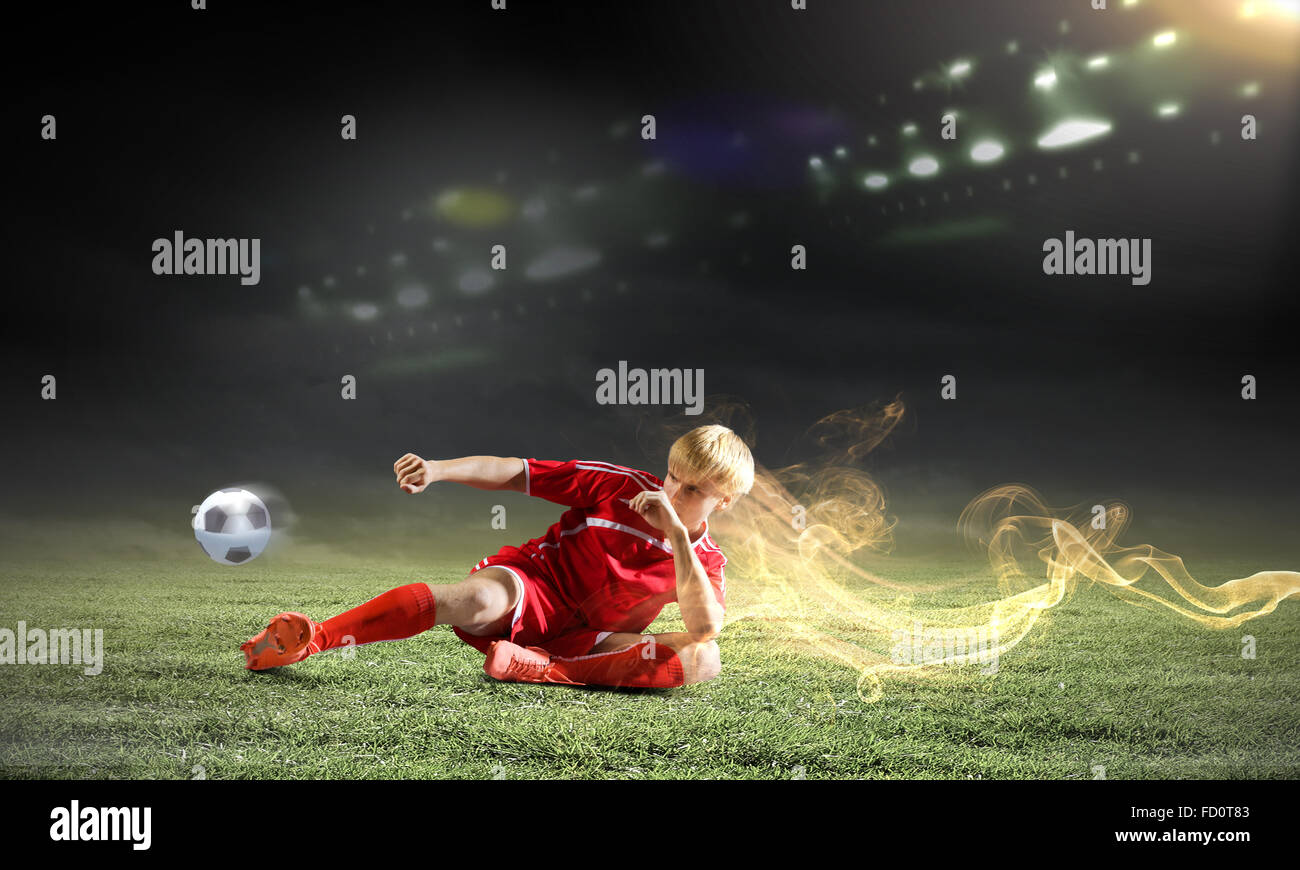 Young football player on stadium doing slide tackle Stock Photo - Alamy