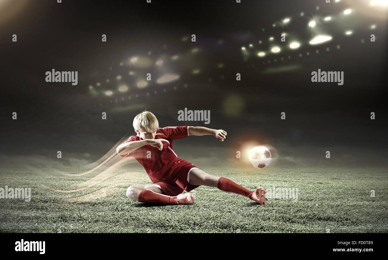 Young football player on stadium doing slide tackle Stock Photo - Alamy