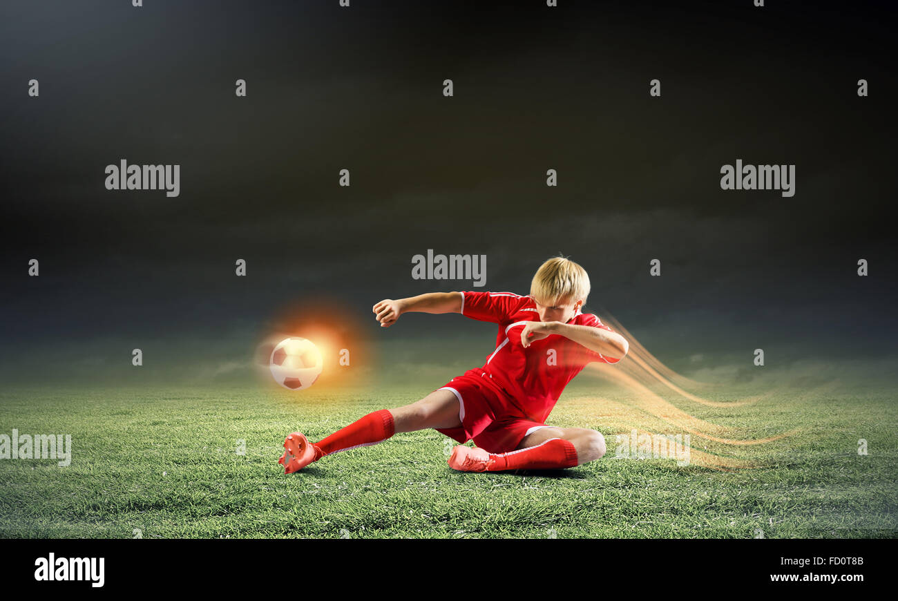 Young football player on stadium doing slide tackle Stock Photo - Alamy