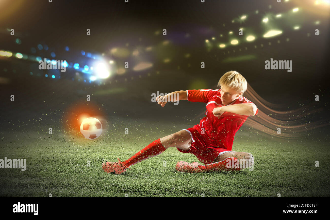 Young football player on stadium doing slide tackle Stock Photo - Alamy