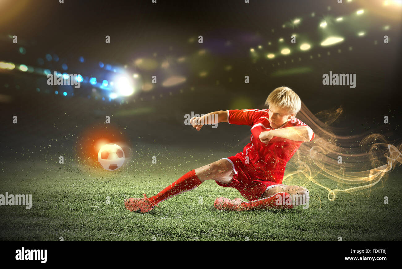 Young football player on stadium doing slide tackle Stock Photo - Alamy