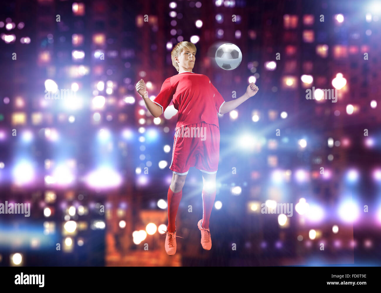 Young football player on stadium kicking ball with head in jump Stock ...